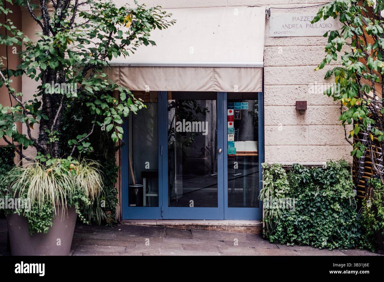 Small restaurant or cafe entrance surrounded by lush plants in a quiet ...