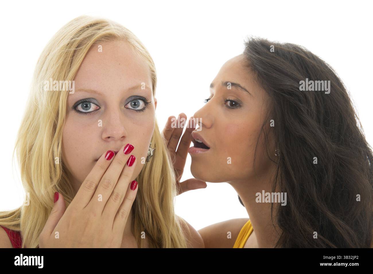 Two girls are talking secrets to each other isolated over white ...