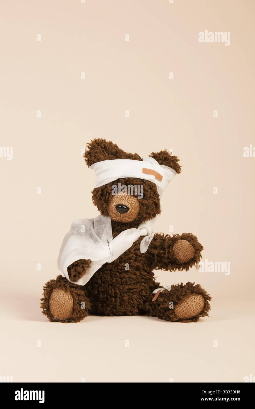 Stuffed hand made bear with pain and plaster sitting on beige ...