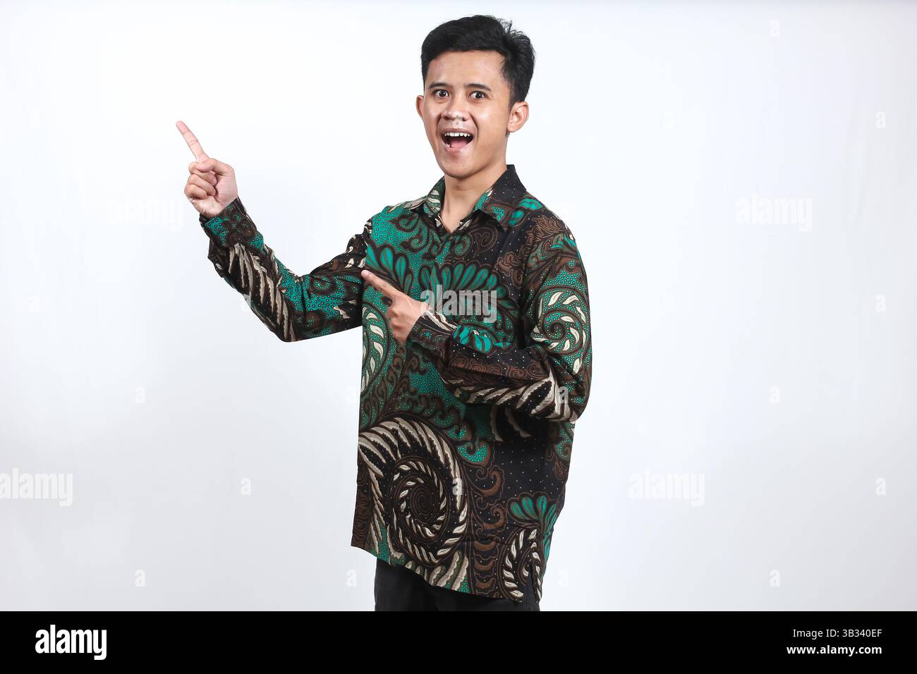 Asian man wearing batik shirt pointing at blank screen with spontaneous ...
