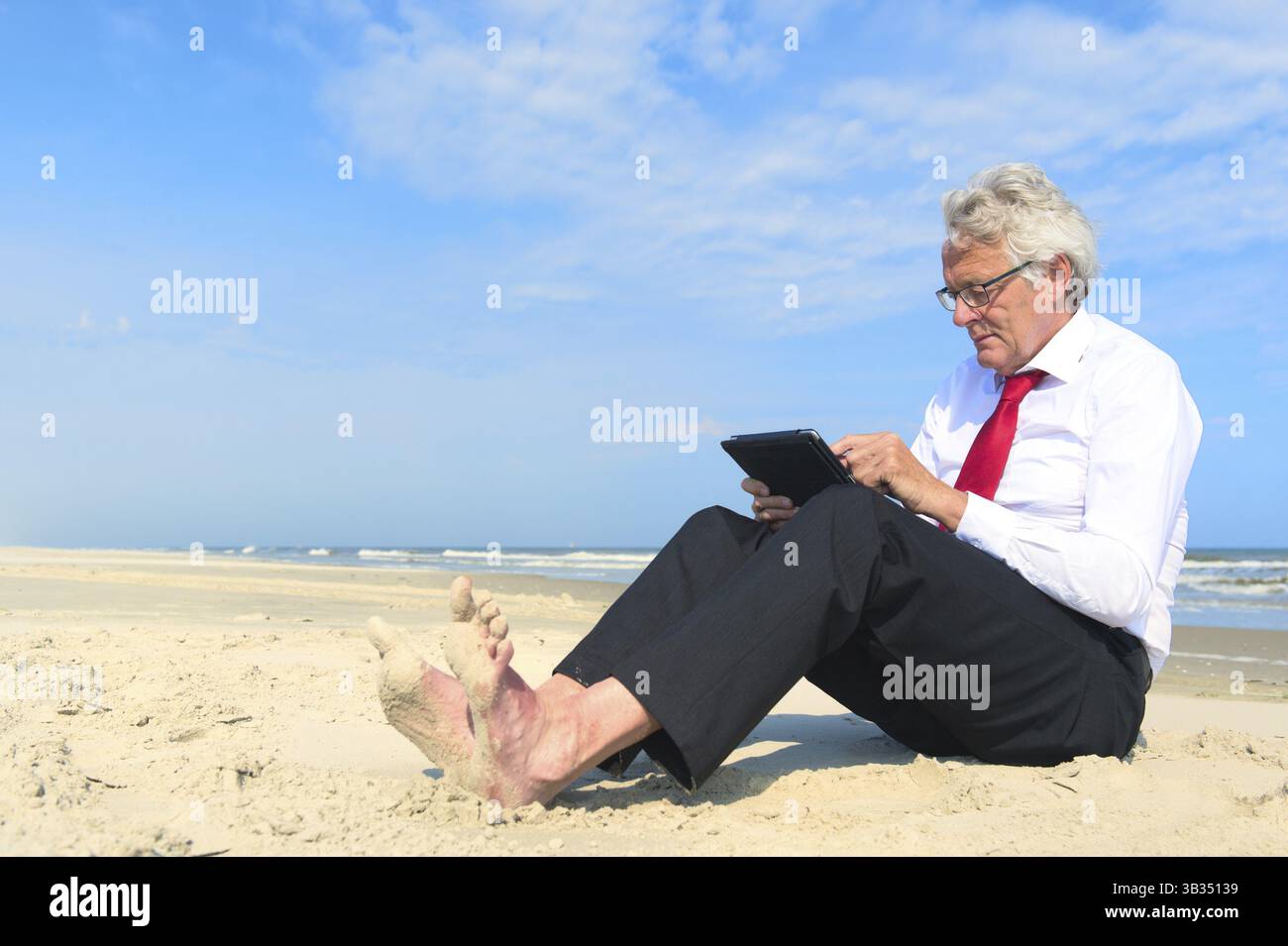 Business man in formal suit sitting and working with tablet at the ...