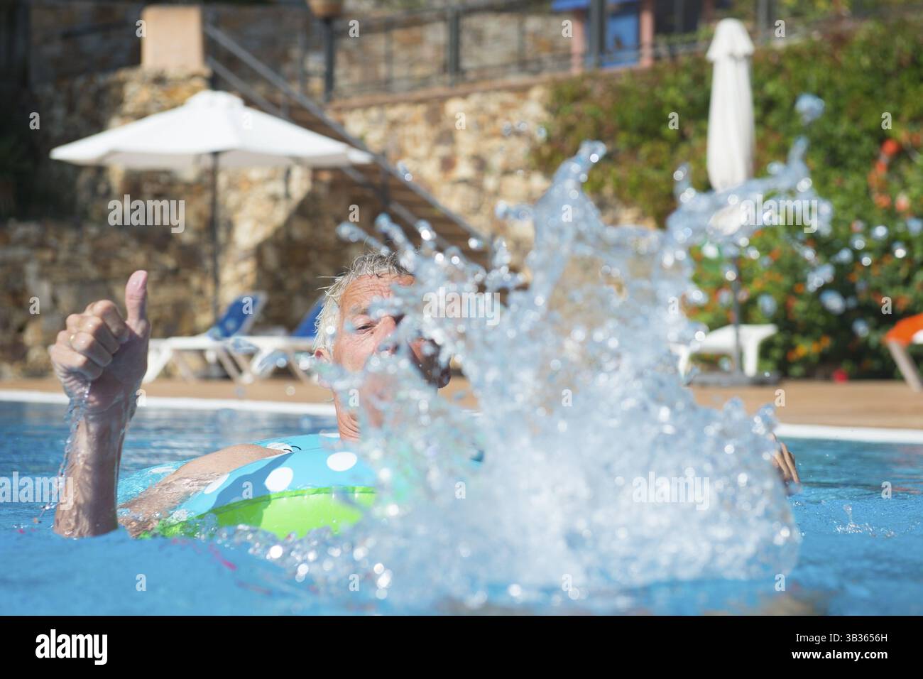 Vacation by senior man playing with splash in swimming pool Stock Photo ...