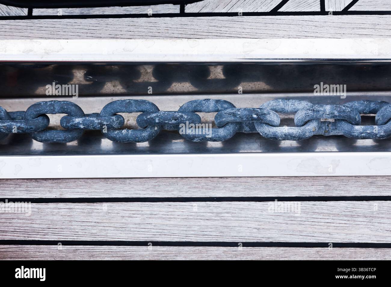 Anchor chain in a stainless steel niche, on the teak deck of a yacht ...
