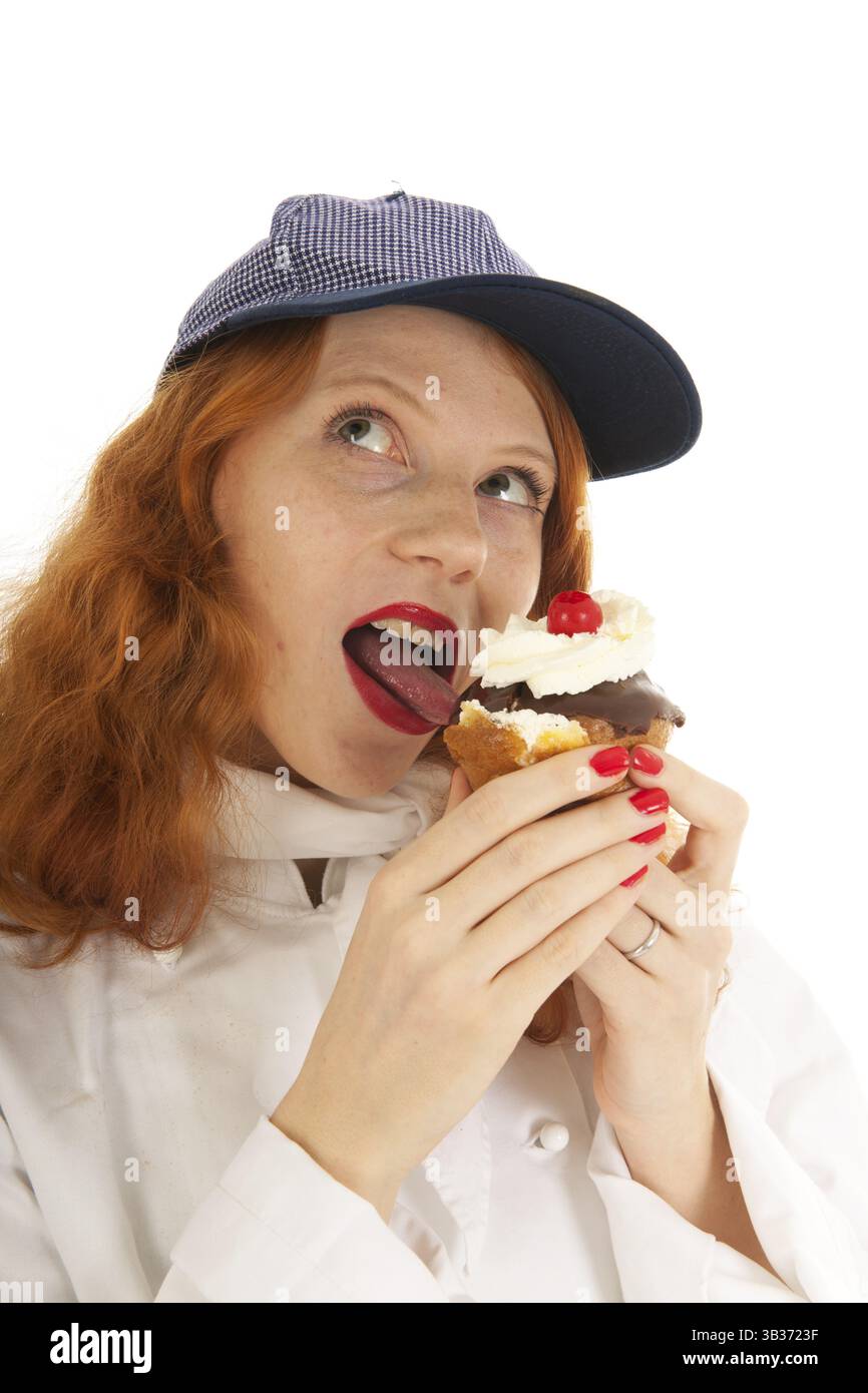 Female baker chef with red hair eating pastry isolated over white ...