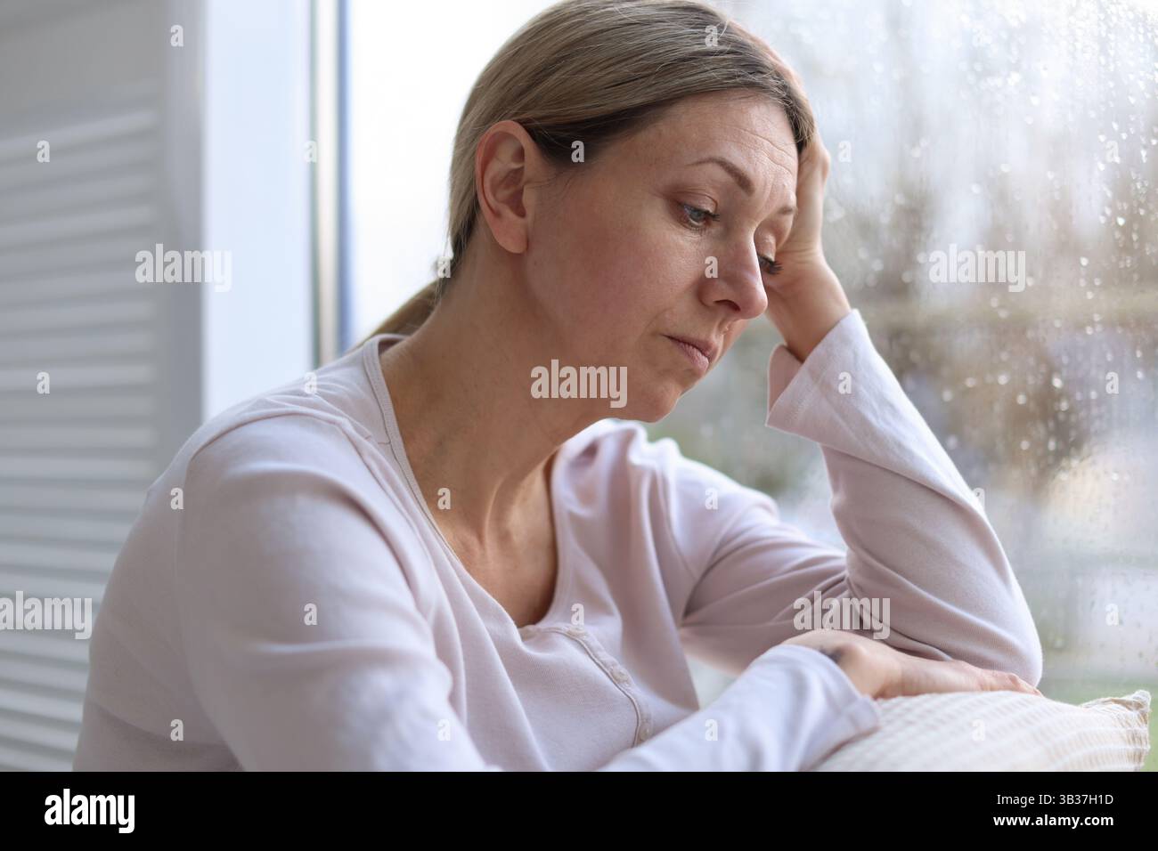 Depressed woman near window at home on rainy day Stock Photo - Alamy
