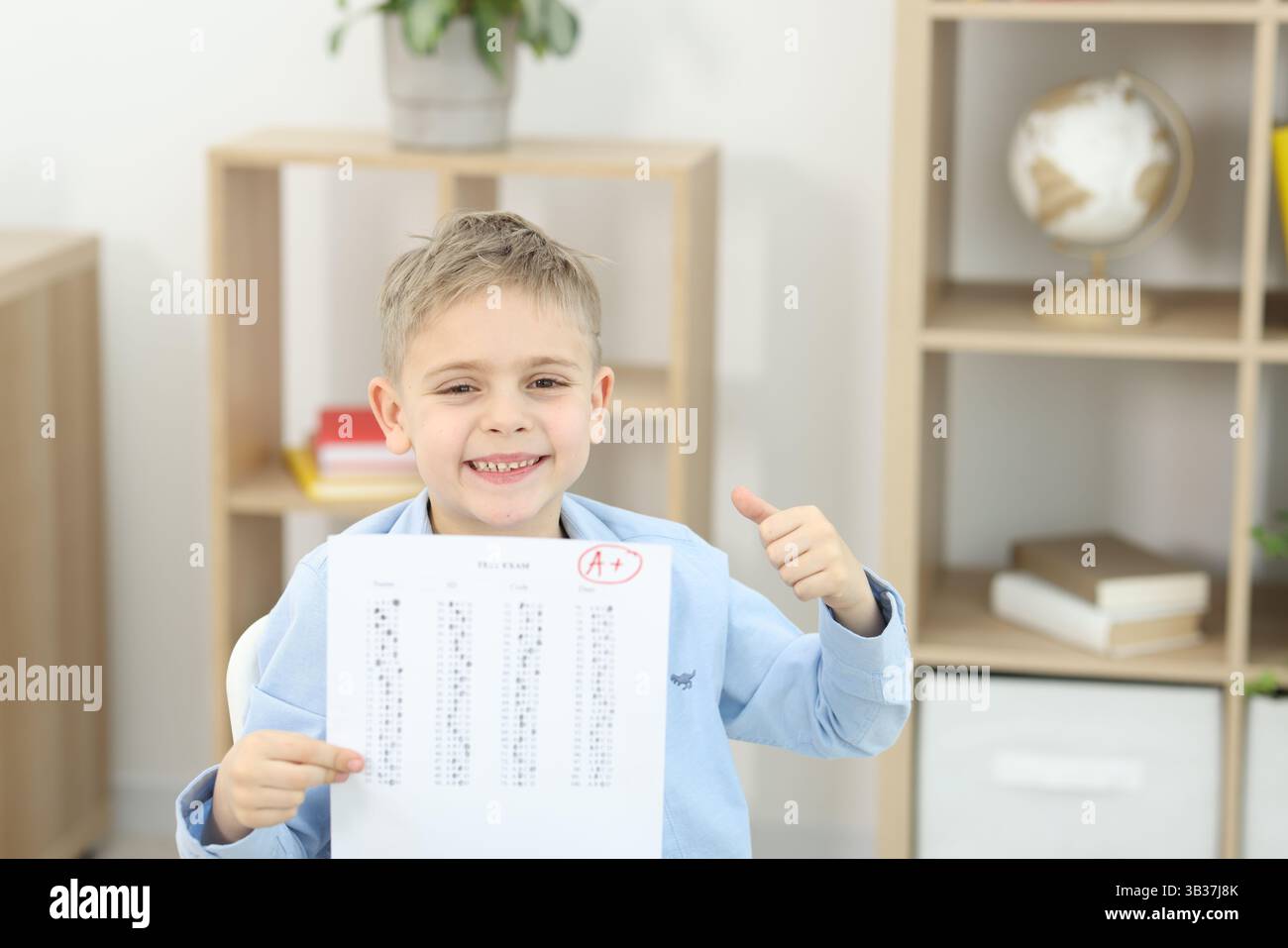 School grade. Happy boy holding answer sheet with letter A and plus ...