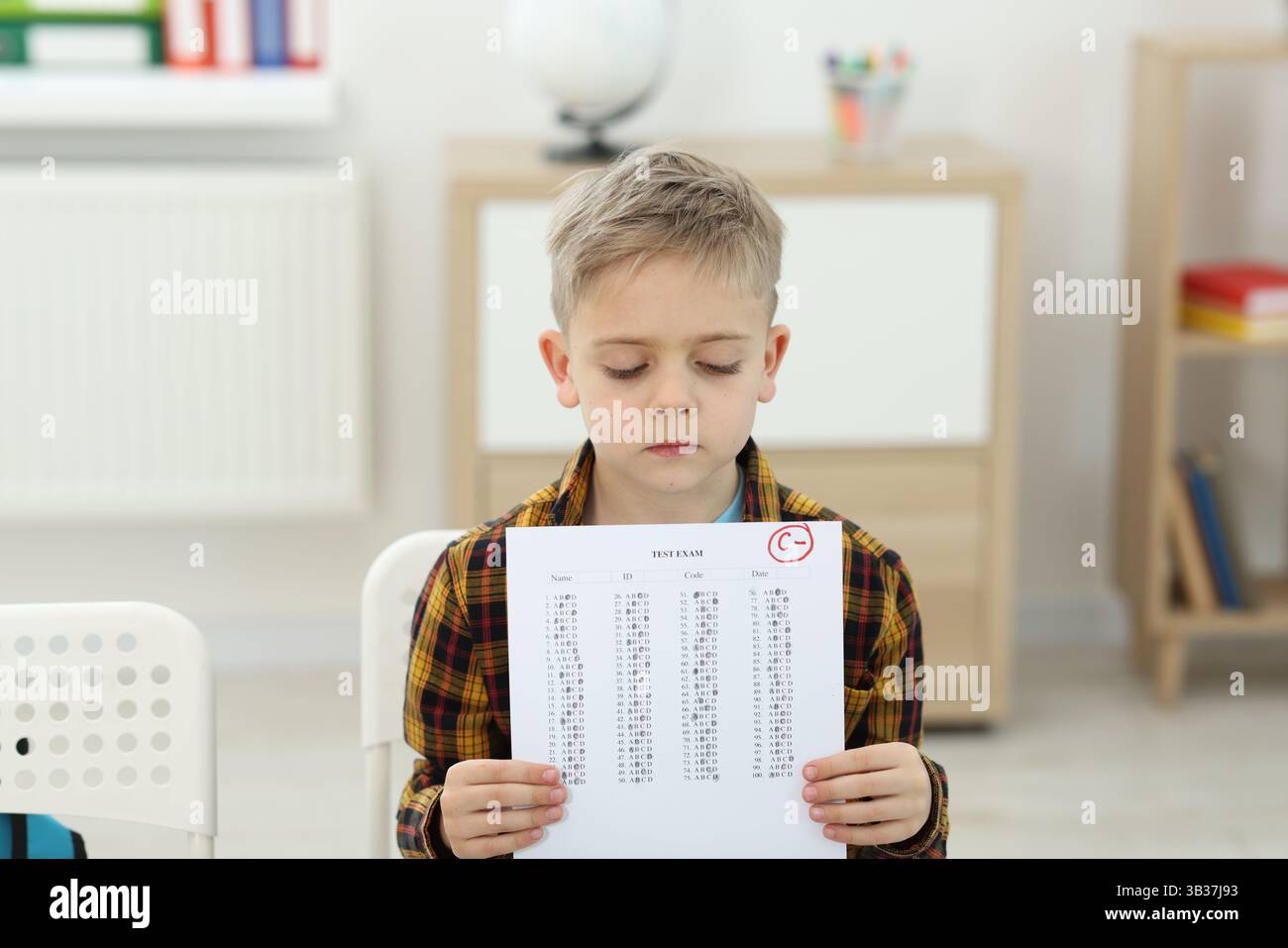 School grade. Sad boy holding answer sheet with letter C and minus ...