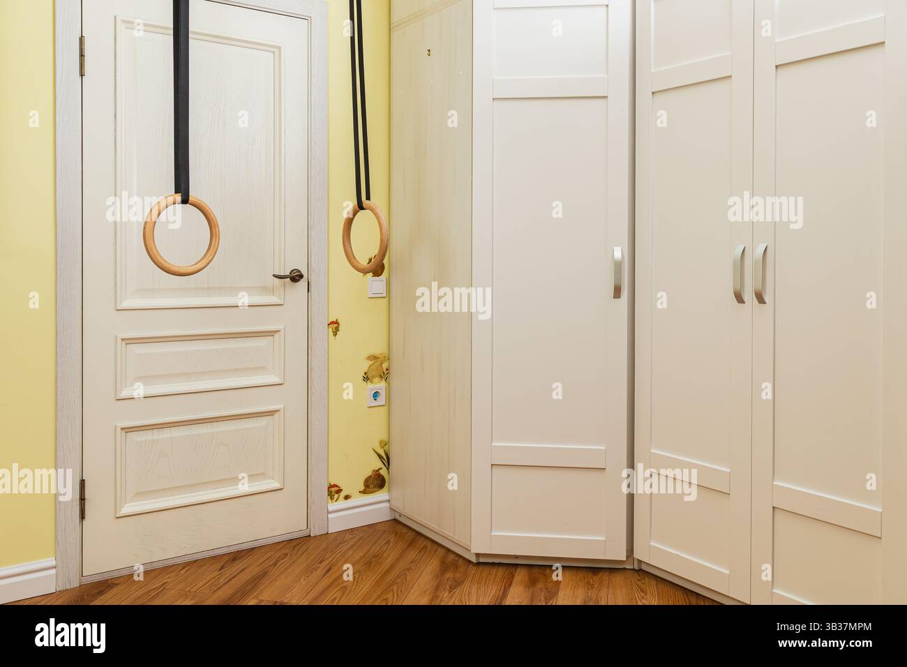 A bright yellow room features wooden gym rings hanging from the ceiling ...