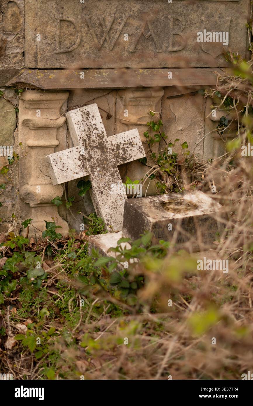 Old stone cross fallen in front of an abandoned and overgrown grave in ...