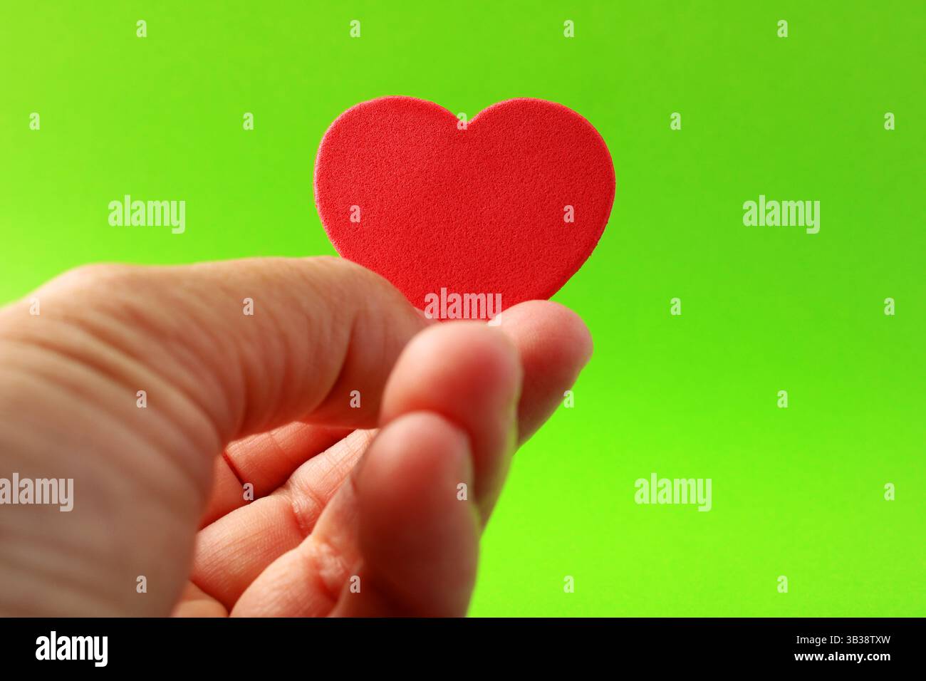 Hand offering a red heart Stock Photo - Alamy