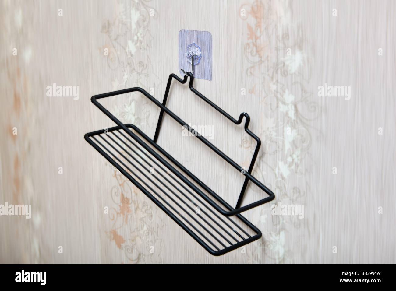 Black metal rack with horizontal bars is hanging on transparent suction ...