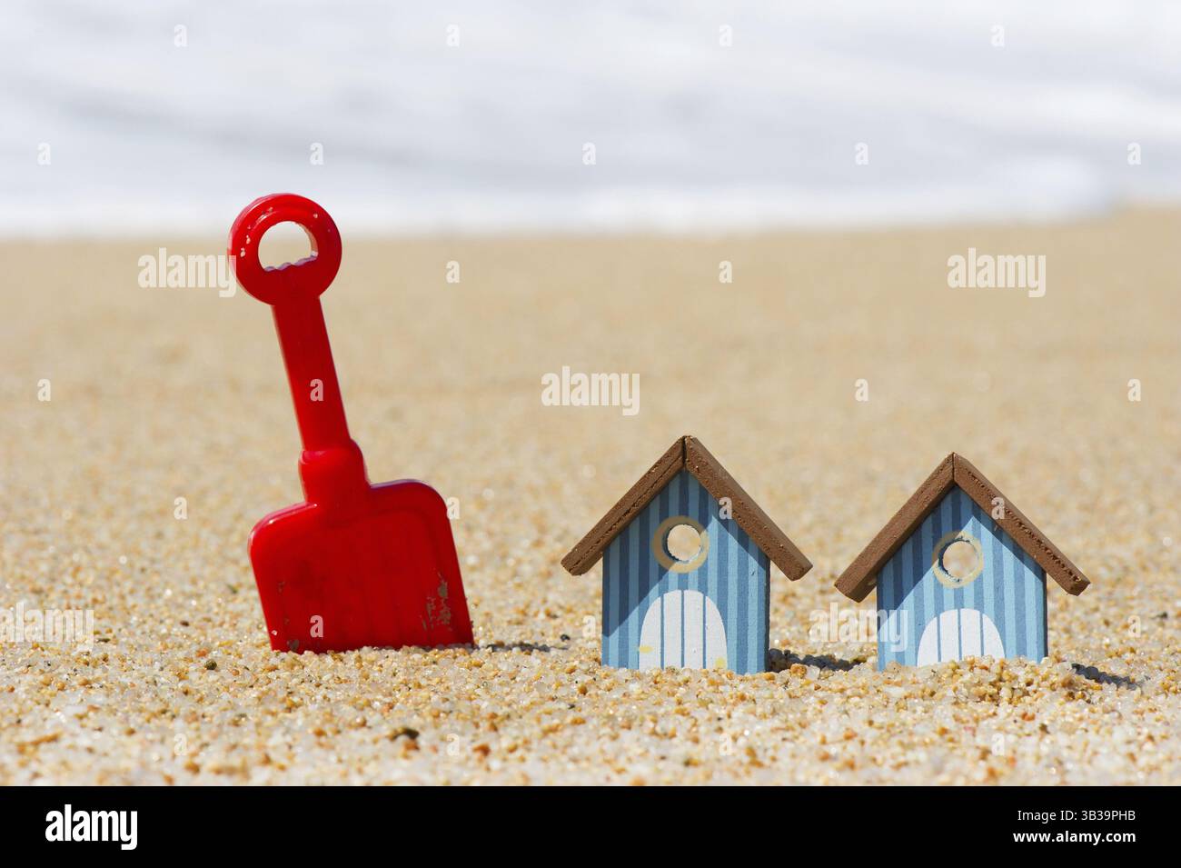 Miniature beach huts with red plastic shovel Stock Photo - Alamy