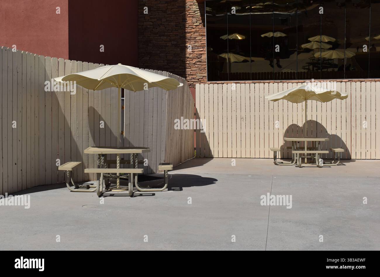 Empty cafe tables with benches and sun umbrellas under the blazing sun ...