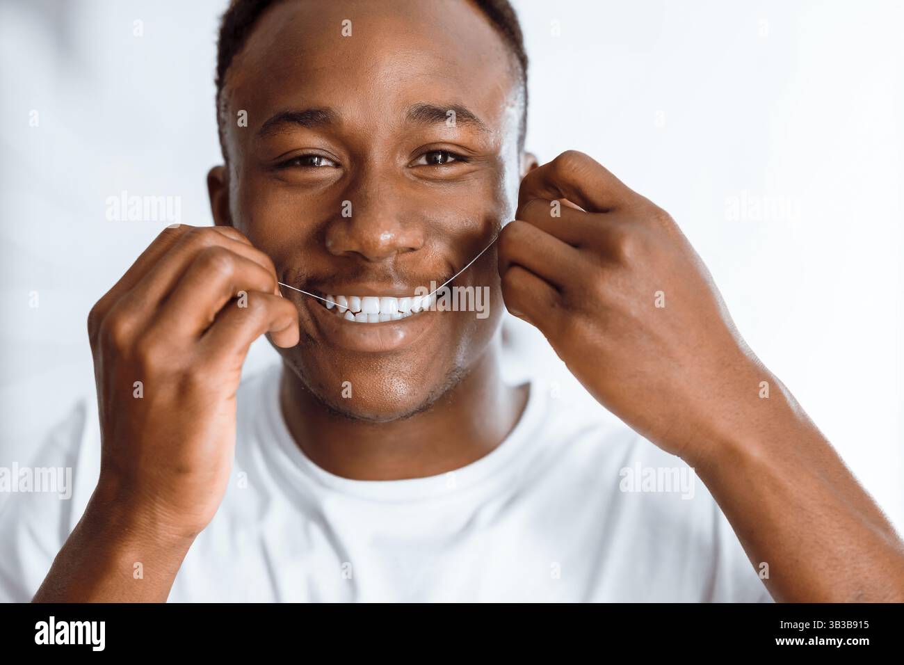 Happy Black Man Flossing Teeth Using Dental Floss In Bathroom Stock ...