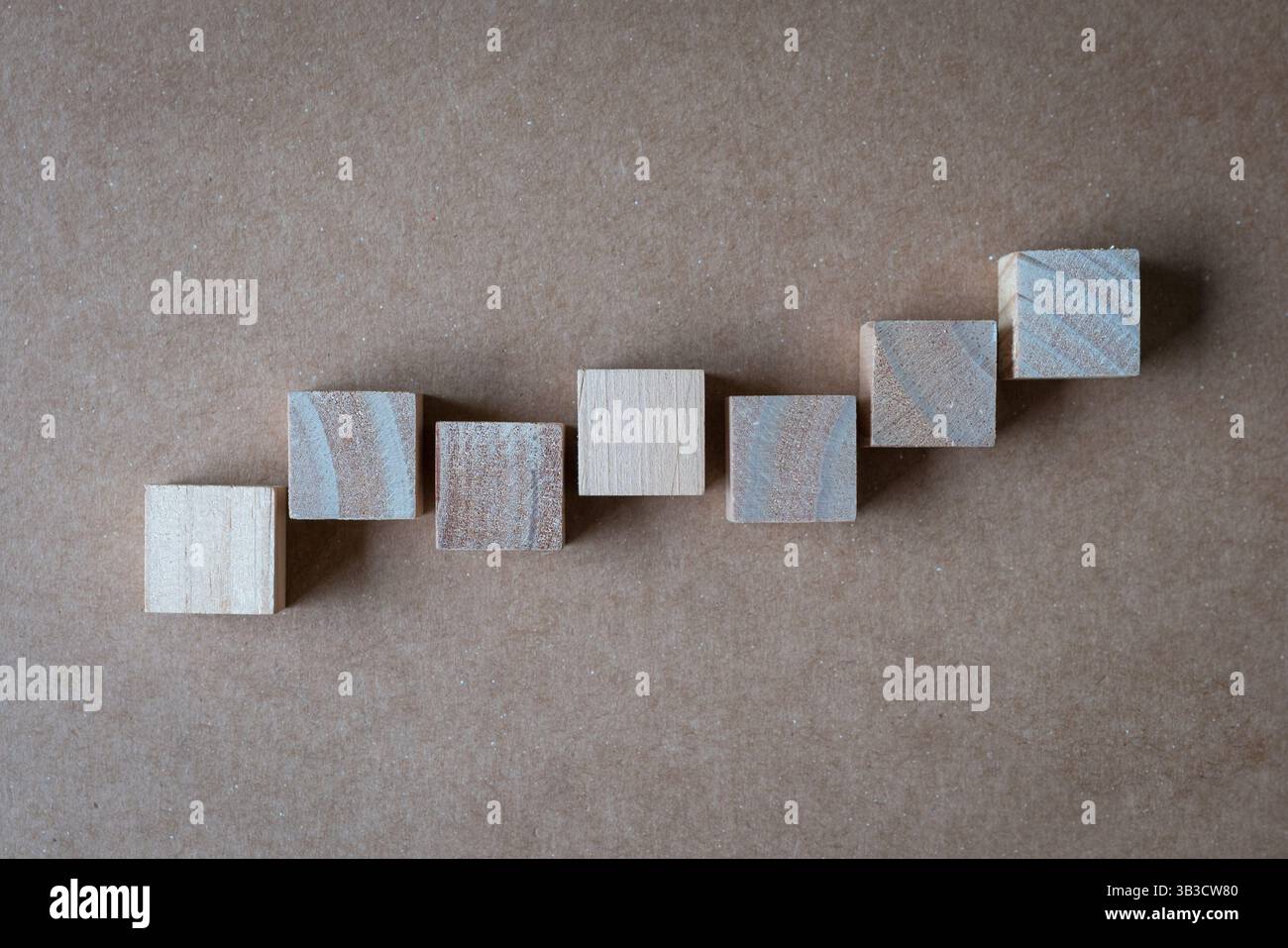 Seven blank square wooden blocks in uneven steps up direction on plain ...