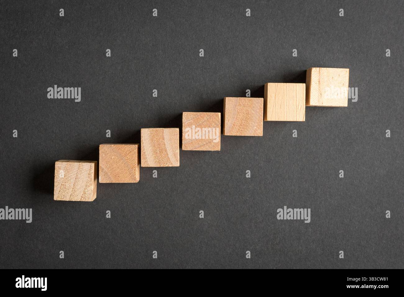 Seven blank square wooden blocks in short steps up direction on dark ...