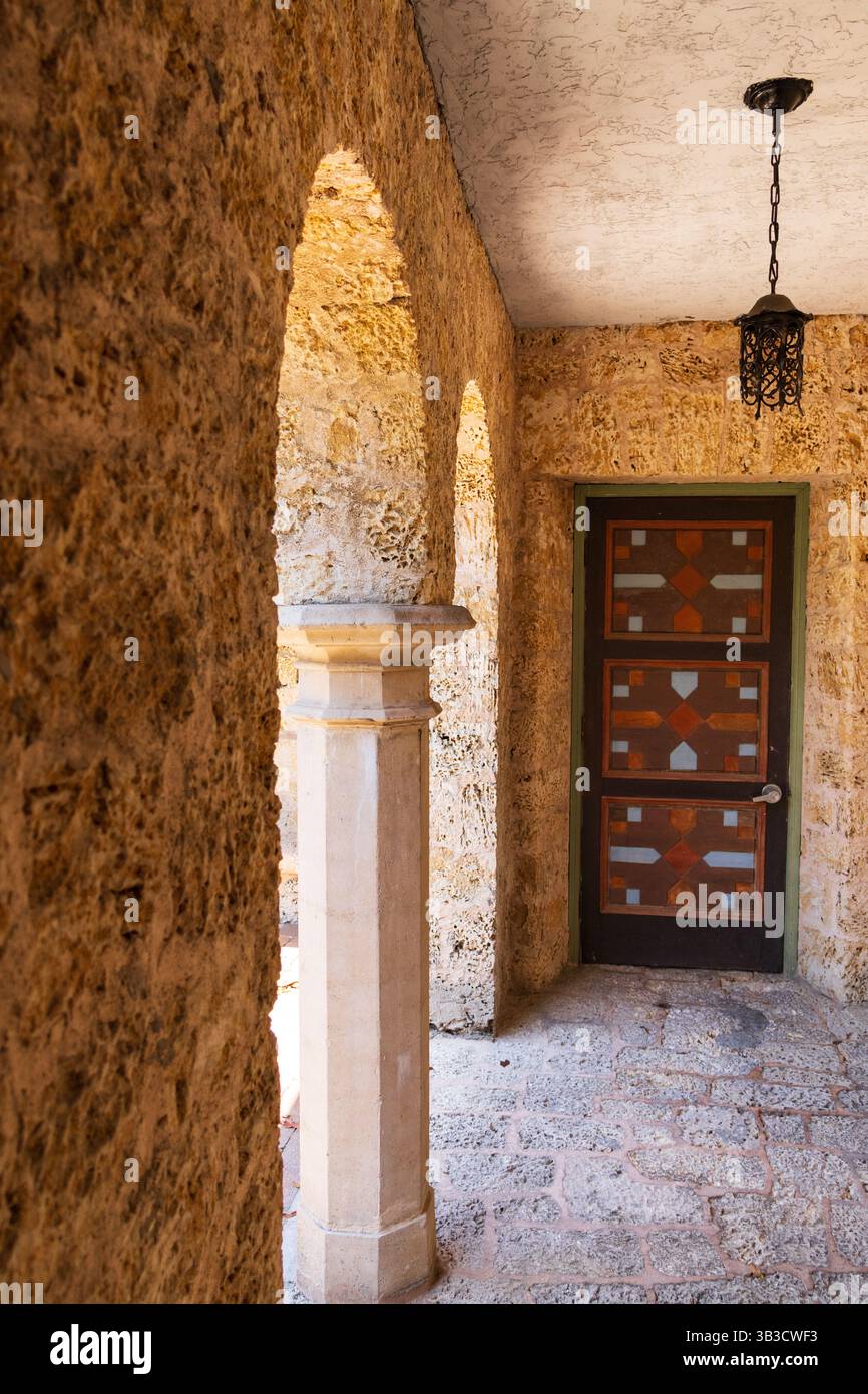 A highly decorated old wooden door at the end of an exterior corridor ...