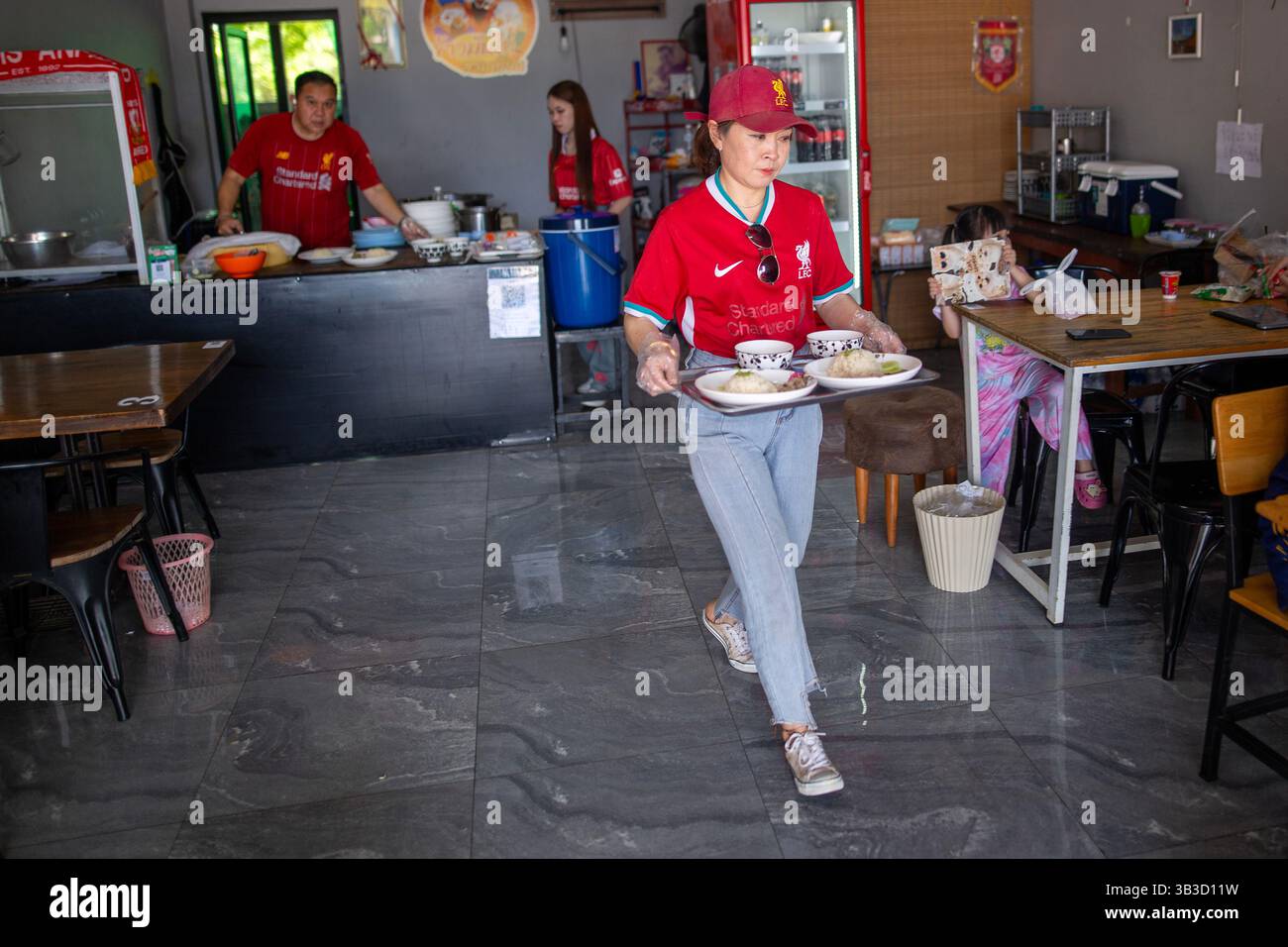 A chicken rice restaurant employee is seen wearing a team jersey while ...