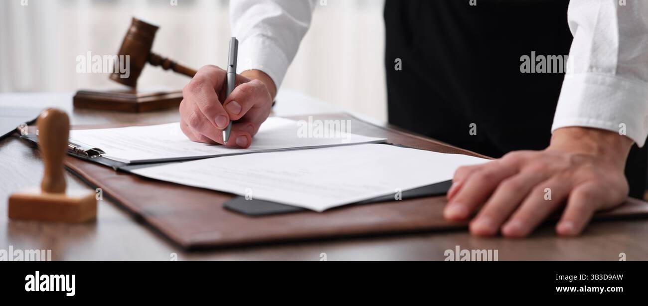 Judge signing document at table, closeup. Banner design Stock Photo - Alamy