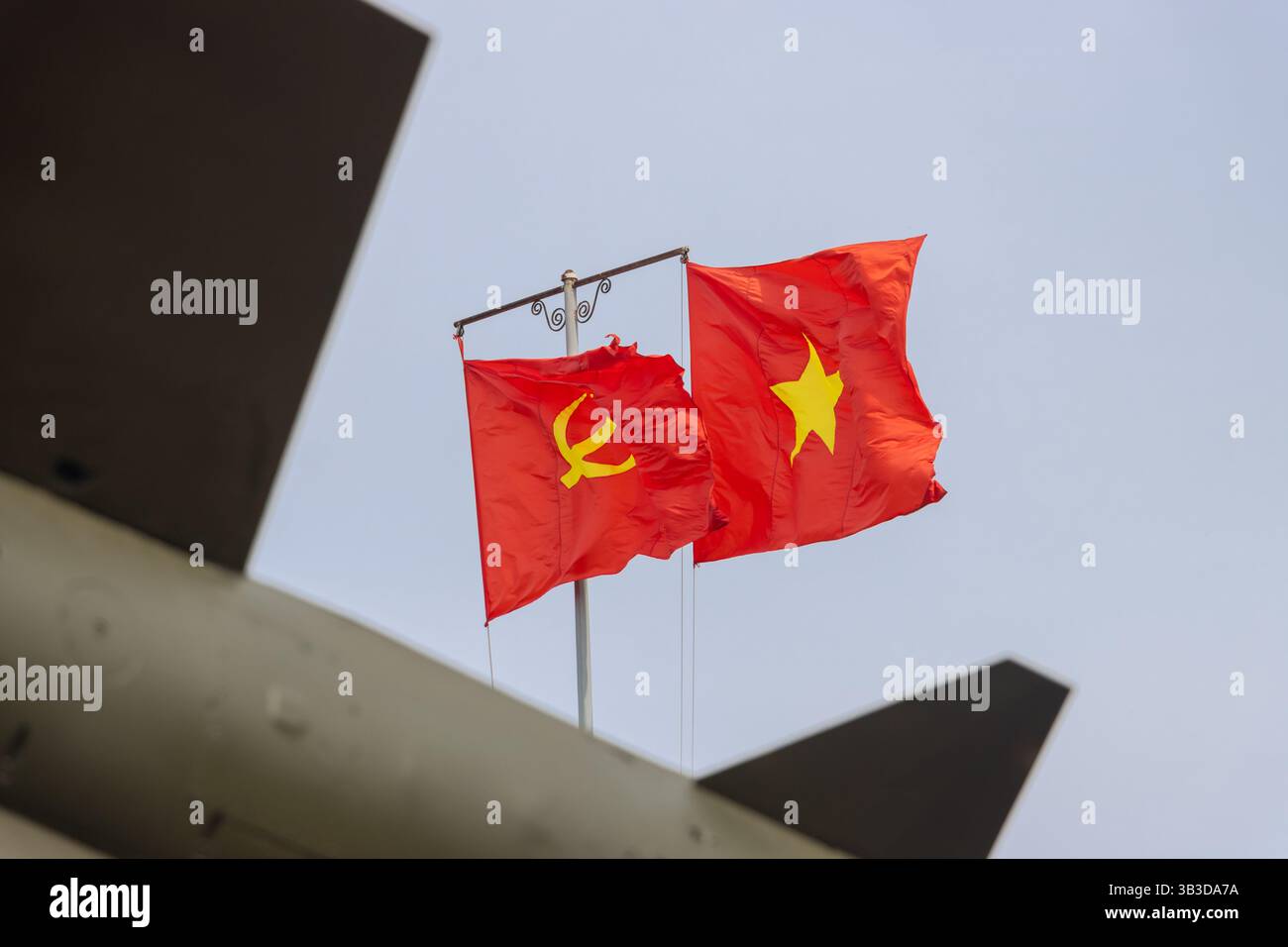 Red flags with communist symbols flutter on a flagpole above a air ...