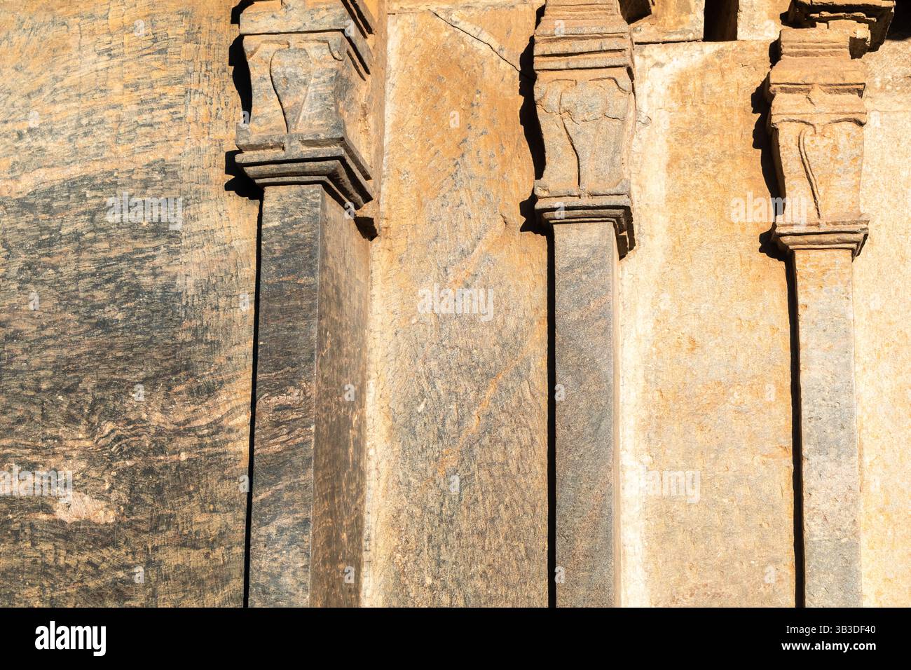 Tall stone pillars with detailed carvings catch the sunlight ...