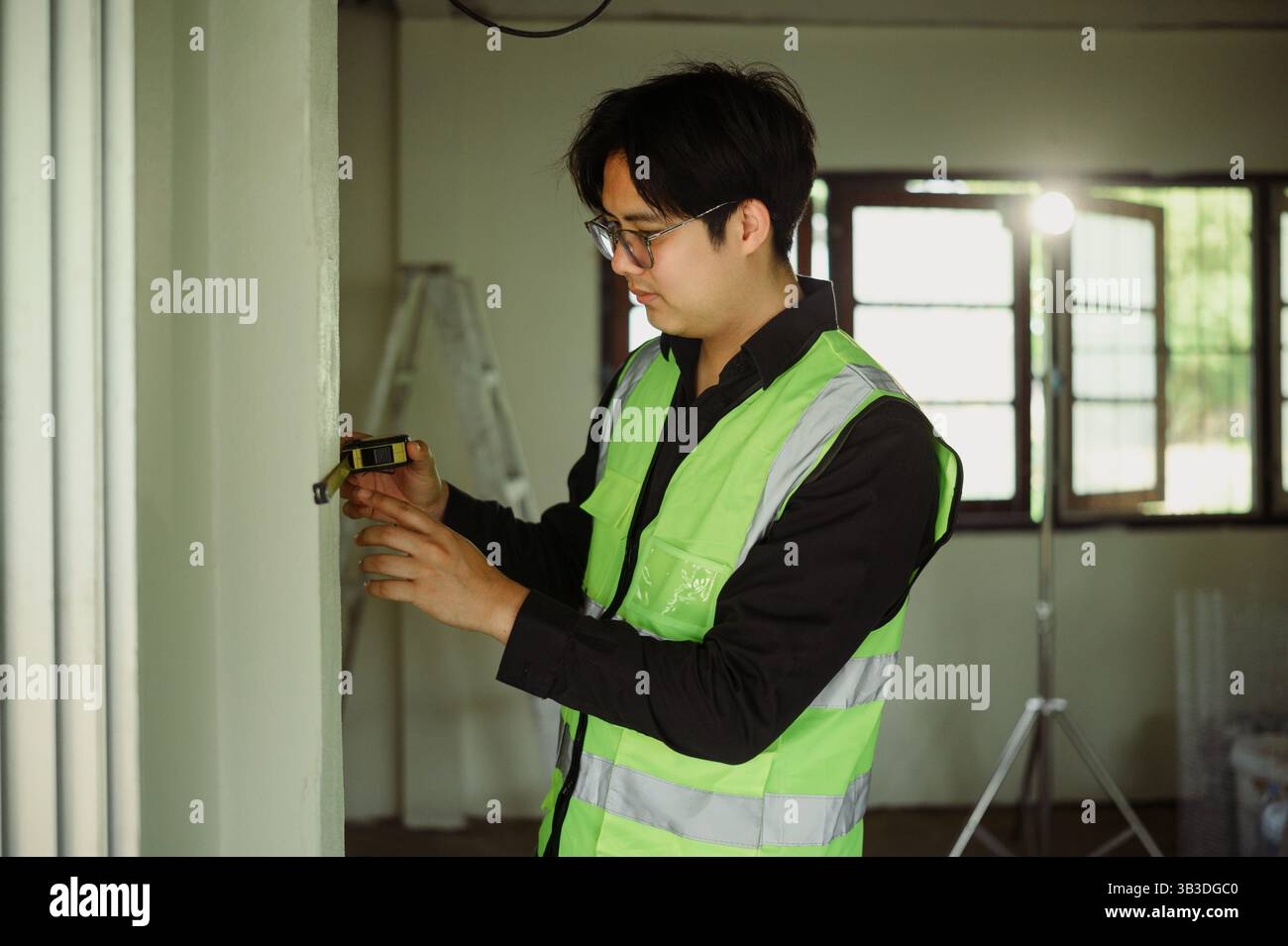 Engineer using a measuring tape to check wall dimensions at ...