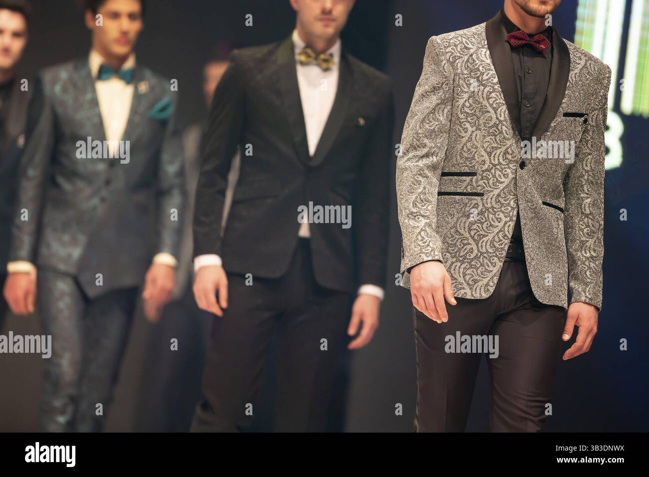 Male models walk the runway in elegant suits during a Fashion Show ...