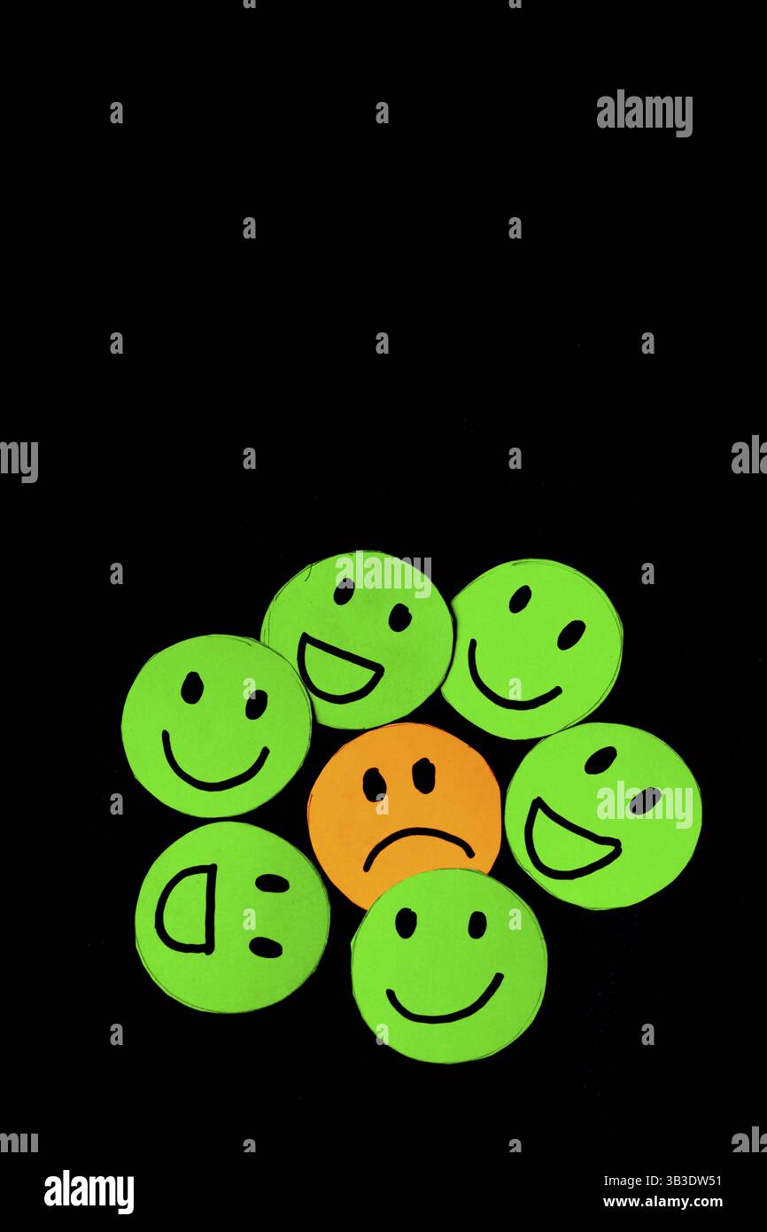 Vertical paper cutout image of green smiley faces surrounding a sad ...