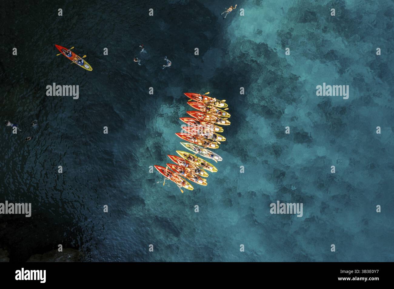 Captain boat sails towards a row of kayaks in the deep turquoise sea ...