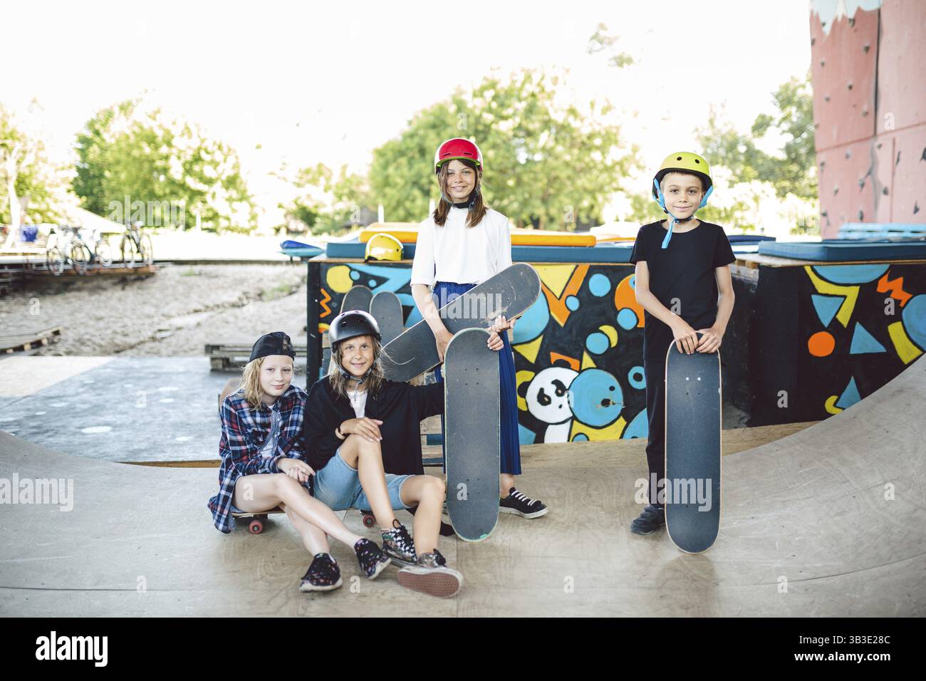 Group of friends athletes skateboarders posing together in a skate park ...