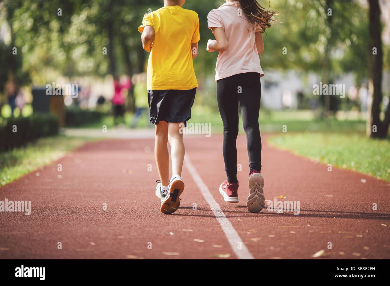 Close-up of legs in trainers of two children on running track of ...