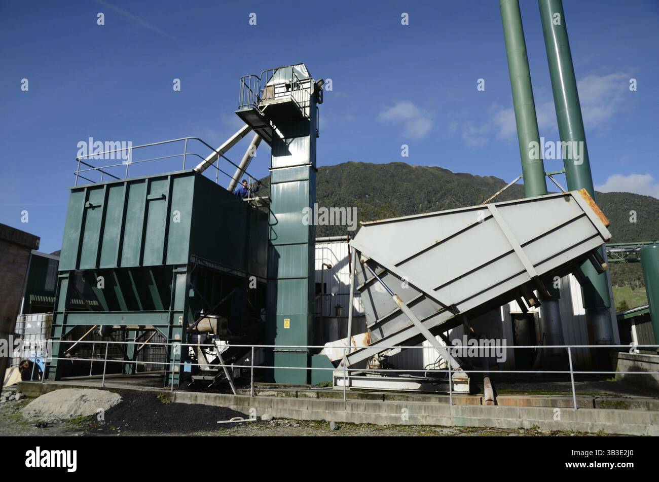 An engineer feeds coal into the hopper that fuels a boiler for a ...