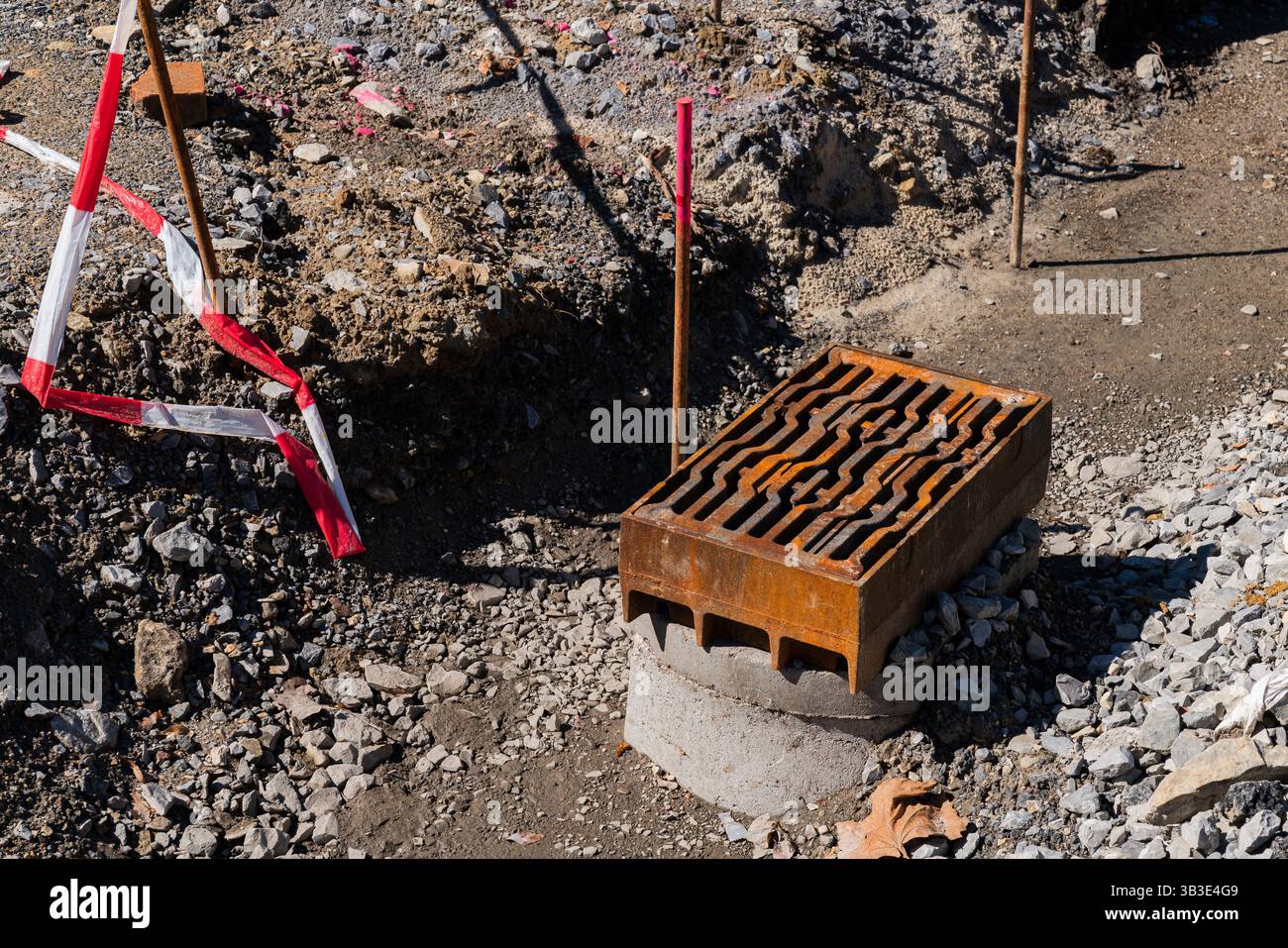 A rusted metal grate rests on a concrete block at a construction site ...