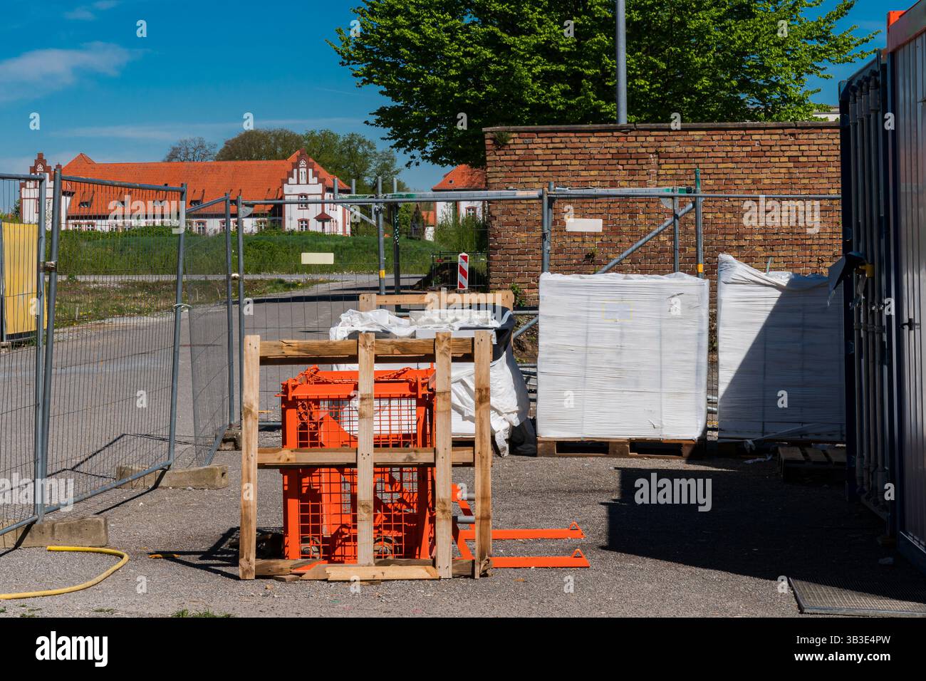 A construction site shows stacked materials and equipment enclosed by ...