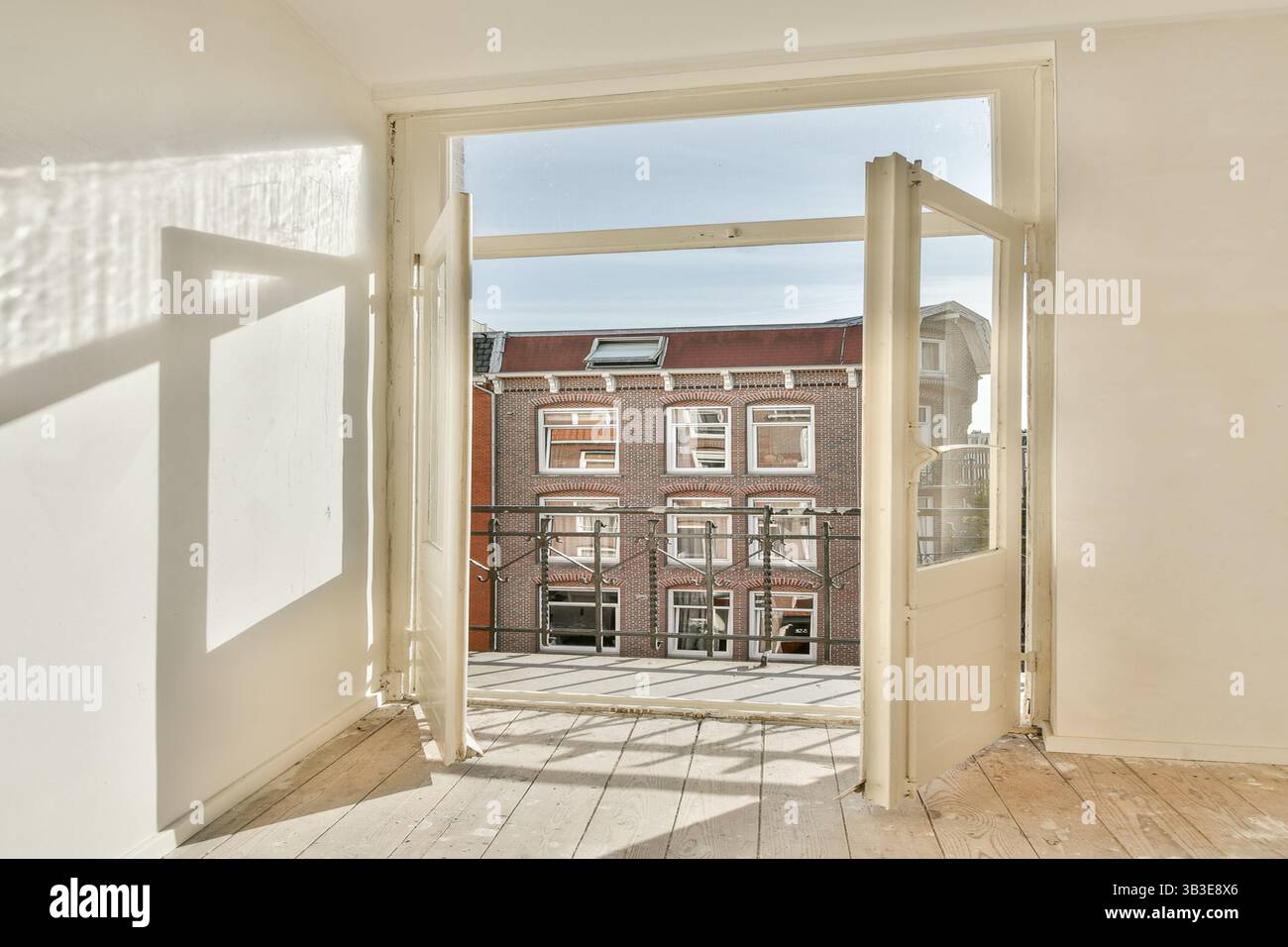 A bright indoor space featuring open doors that lead to a sunny balcony ...