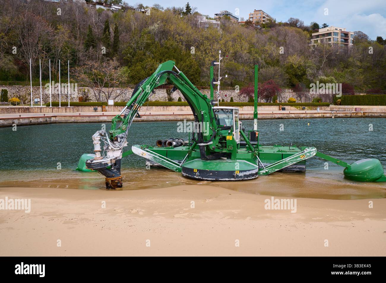Green amphibious dredging machine working at the edge of a beach and ...