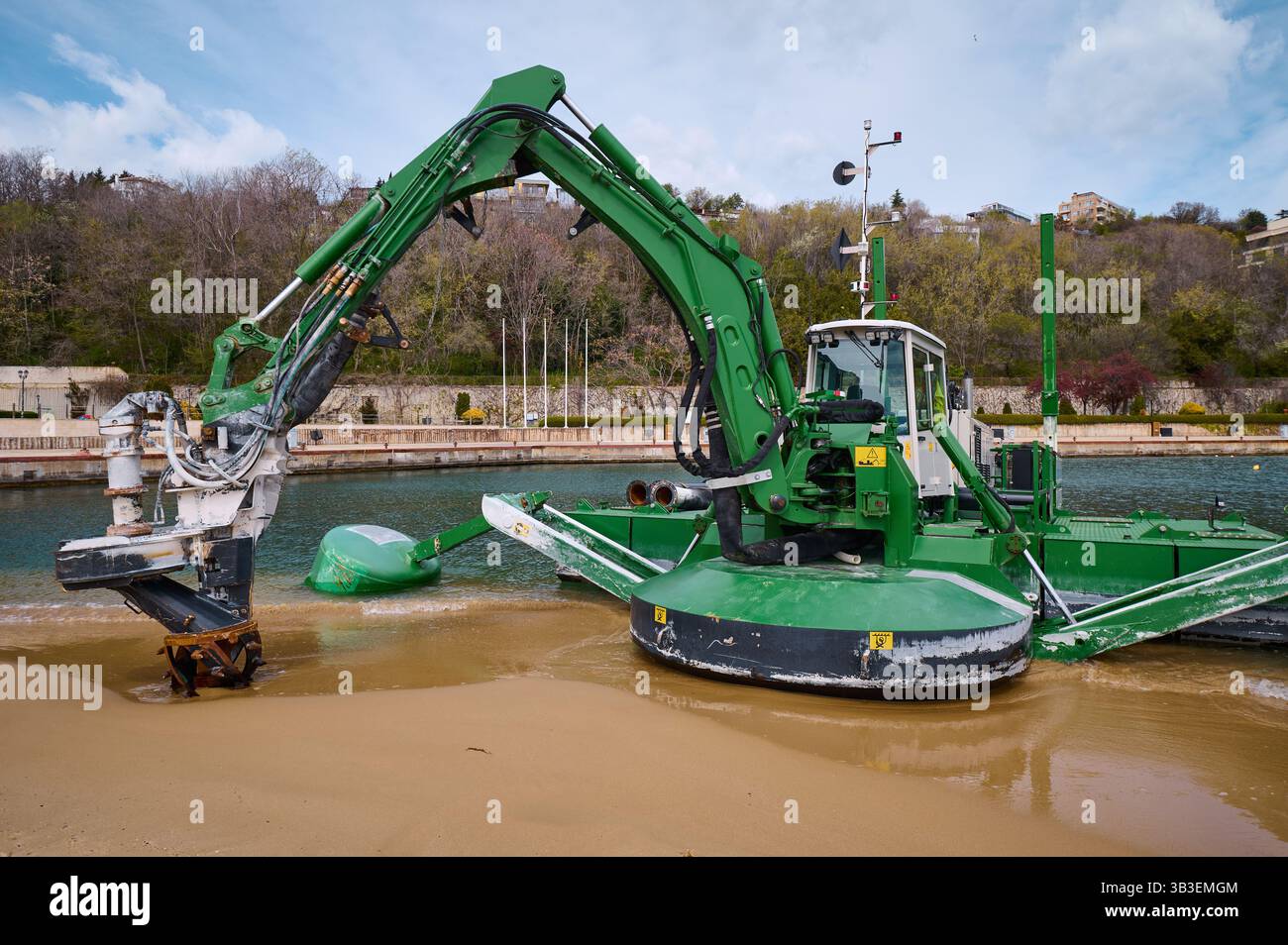 Green amphibious dredging machine working at the edge of a beach and ...
