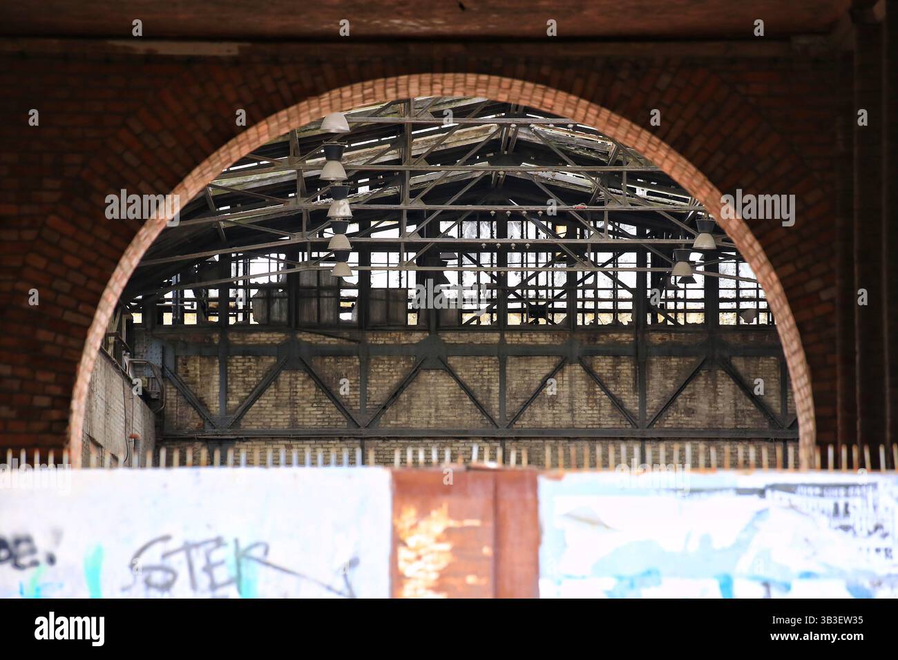 Brick arch behind steel gate framing an abandoned industrial building ...