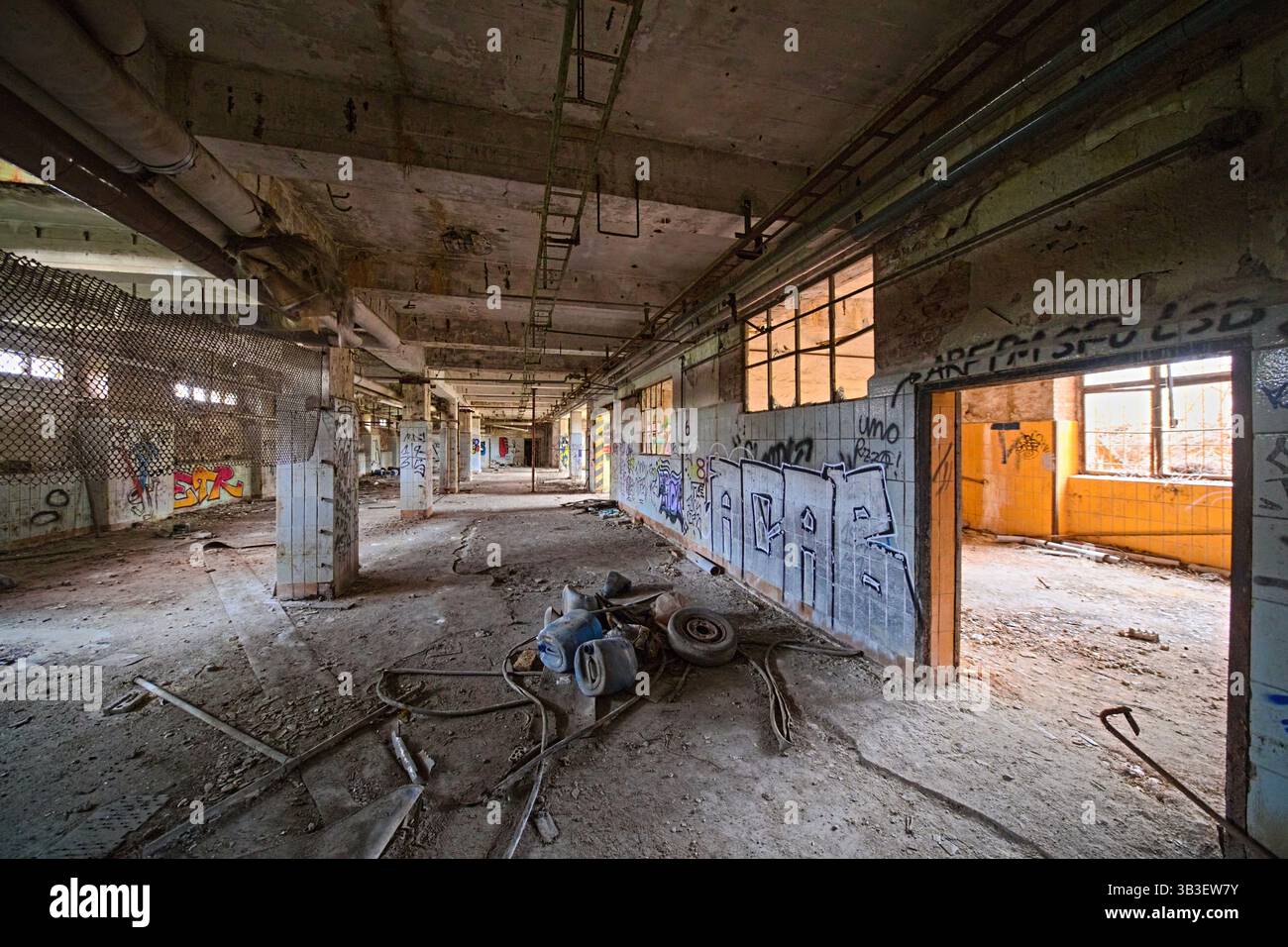 Abandoned factory hall with graffiti-covered walls, broken debris, and ...