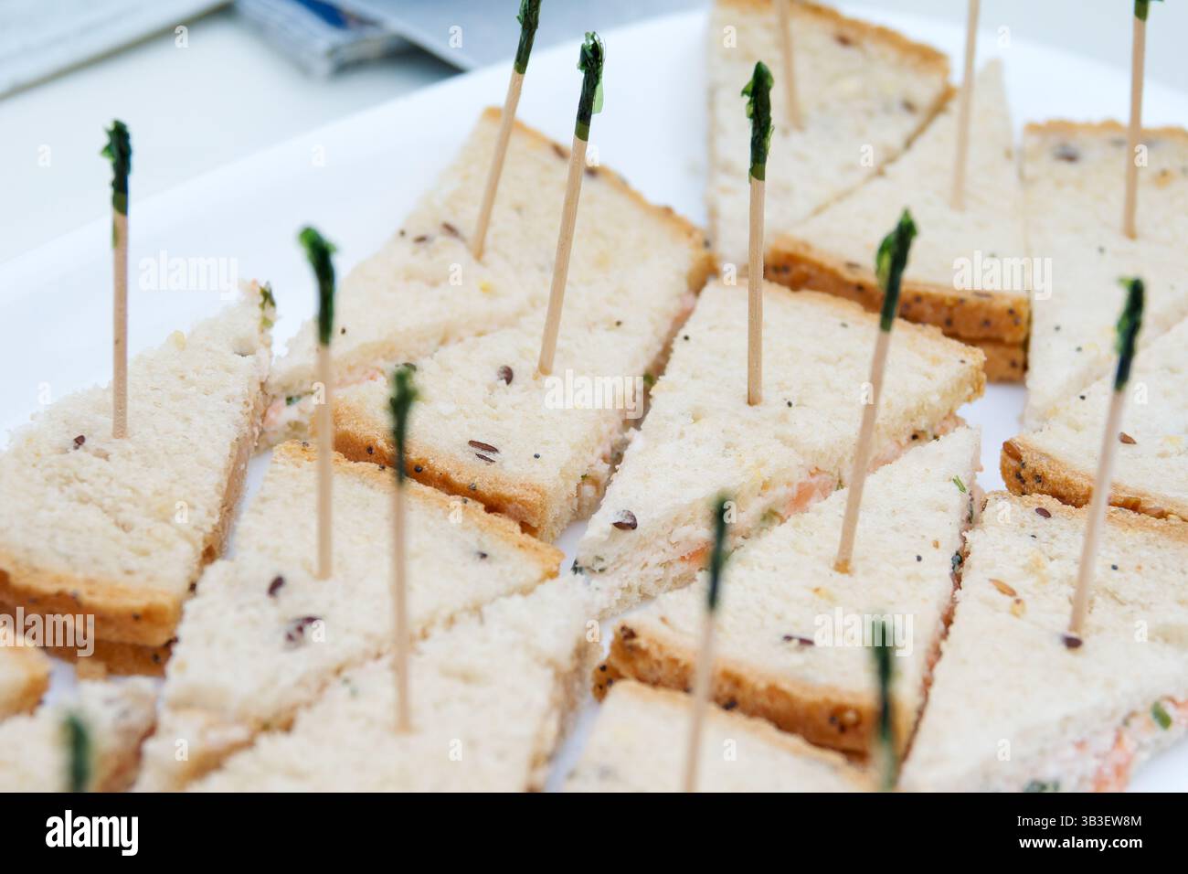 Triangular mini sandwiches with herb garnish on elegant buffet tray ...