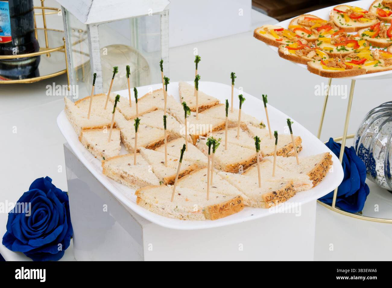 Triangular mini sandwiches with herb garnish on elegant buffet tray ...
