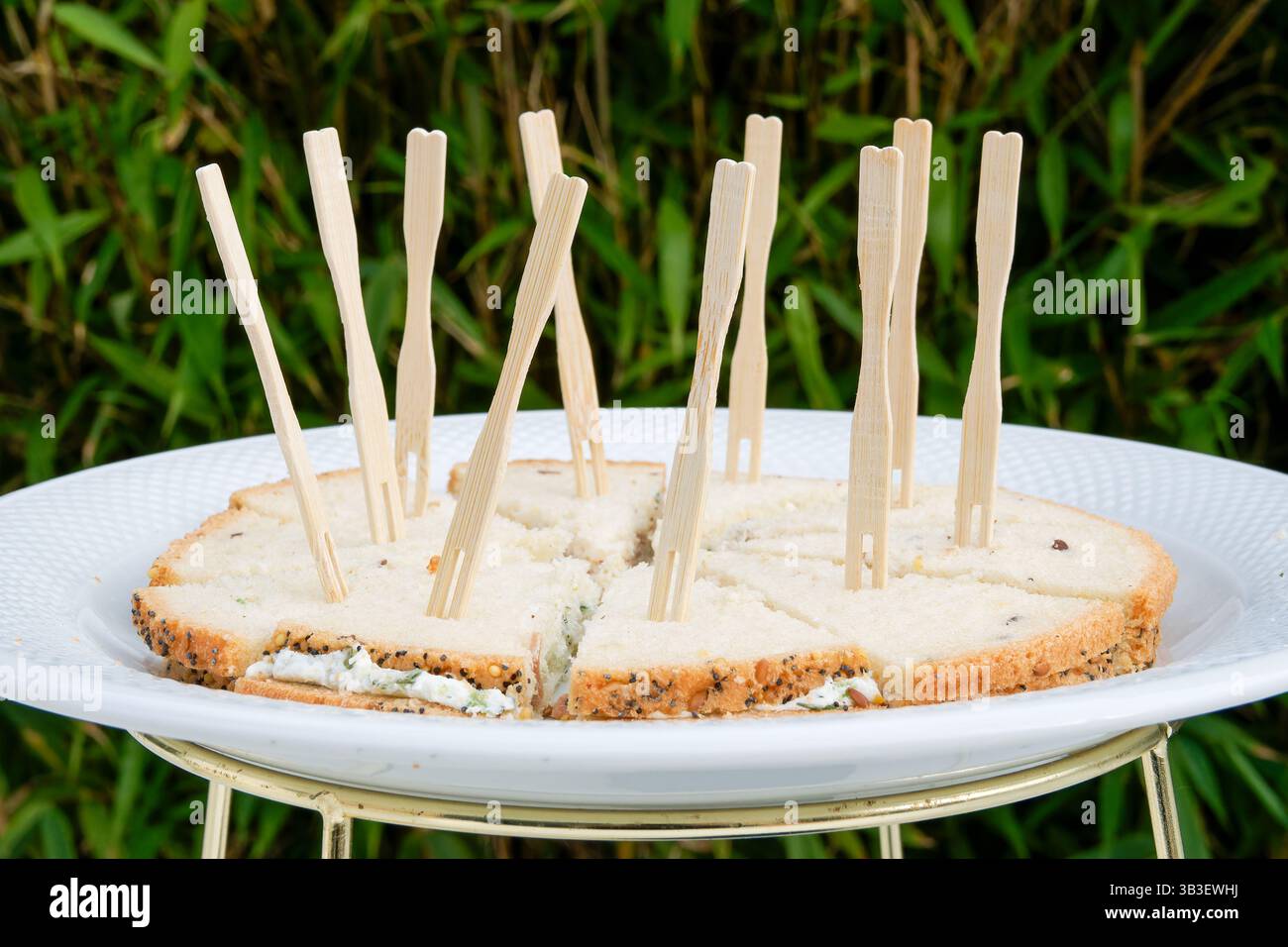 Triangular mini sandwiches with herb garnish on elegant buffet tray ...