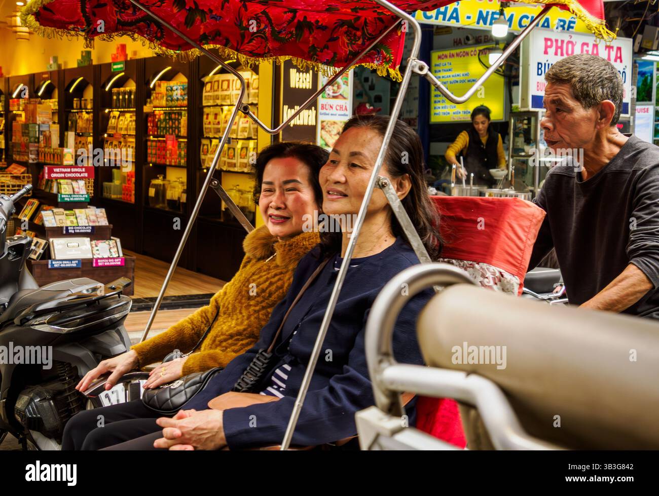 Two women travel in a pedalled cyclo in Hanoi, Vietnam Stock Photo - Alamy
