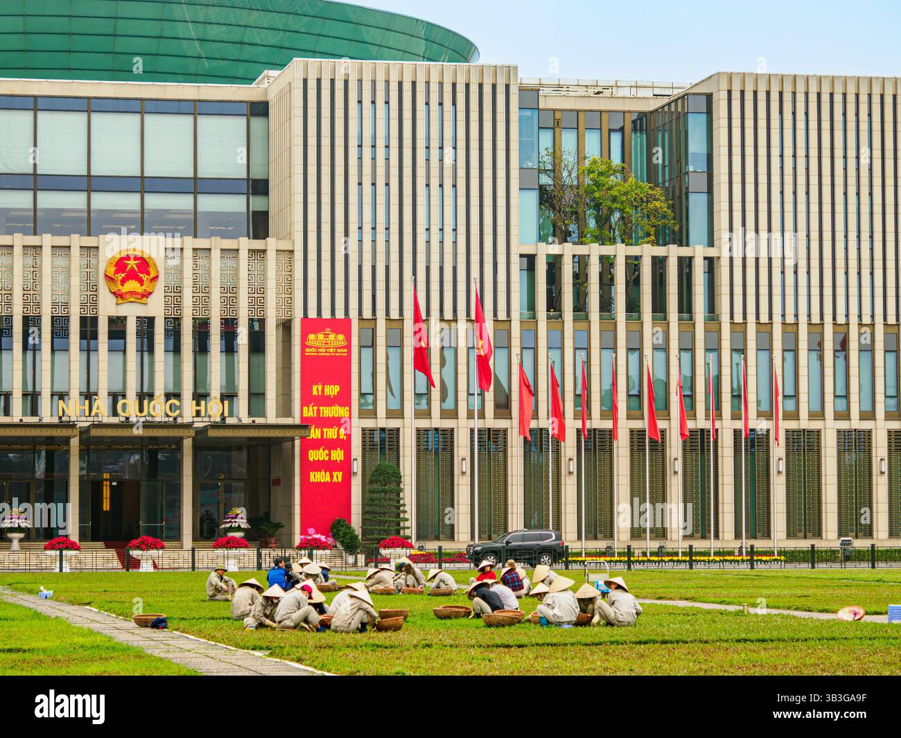 Gardeners in conical hats weed the lawn at the National Assembly ...