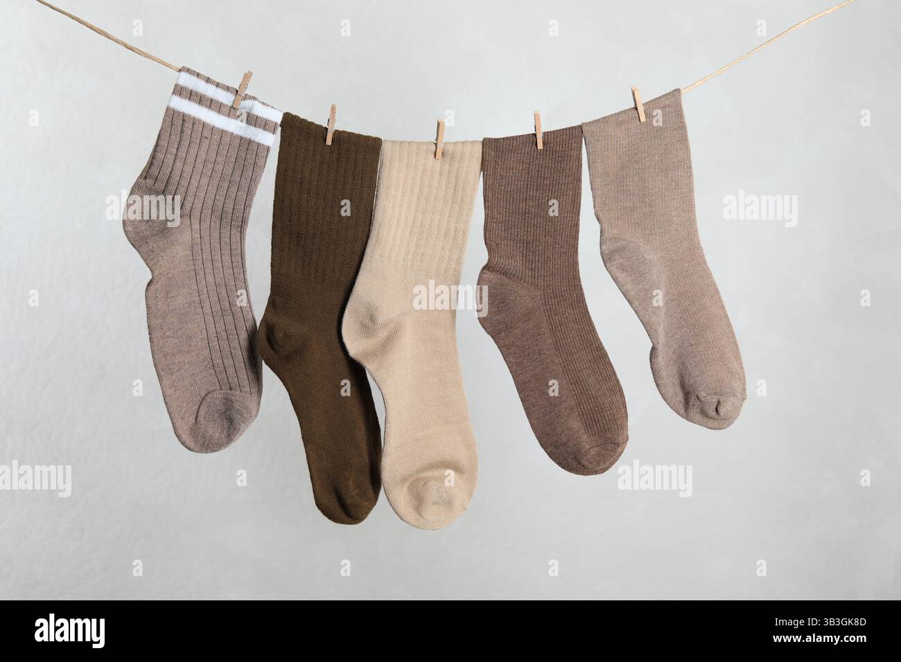 Different socks hanging on washing line against light grey background ...