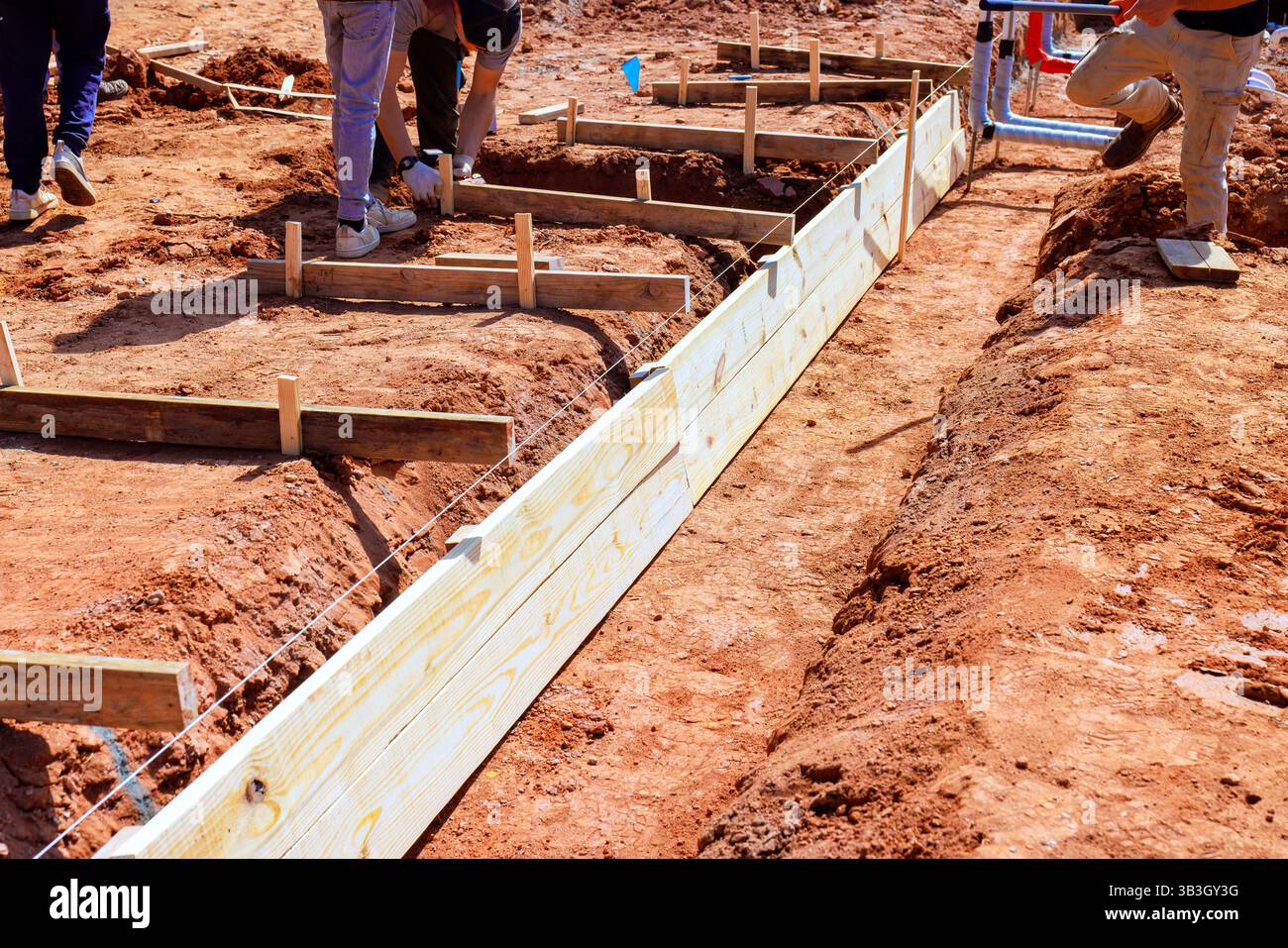 Workers are setting up wooden forms for foundation in construction area ...