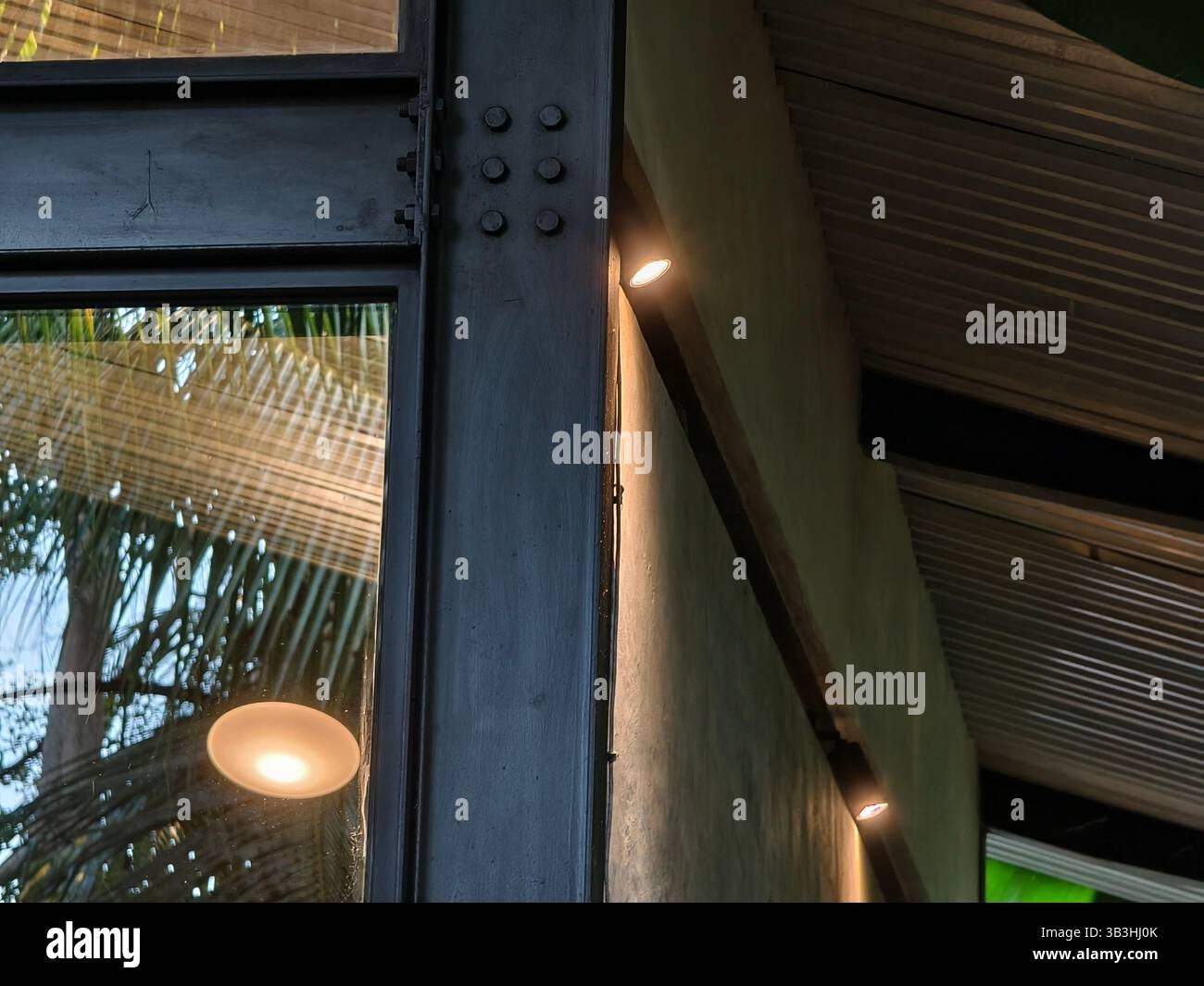 A corner of an industrial style building featuring a steel framed window, exposed bolts, a ...