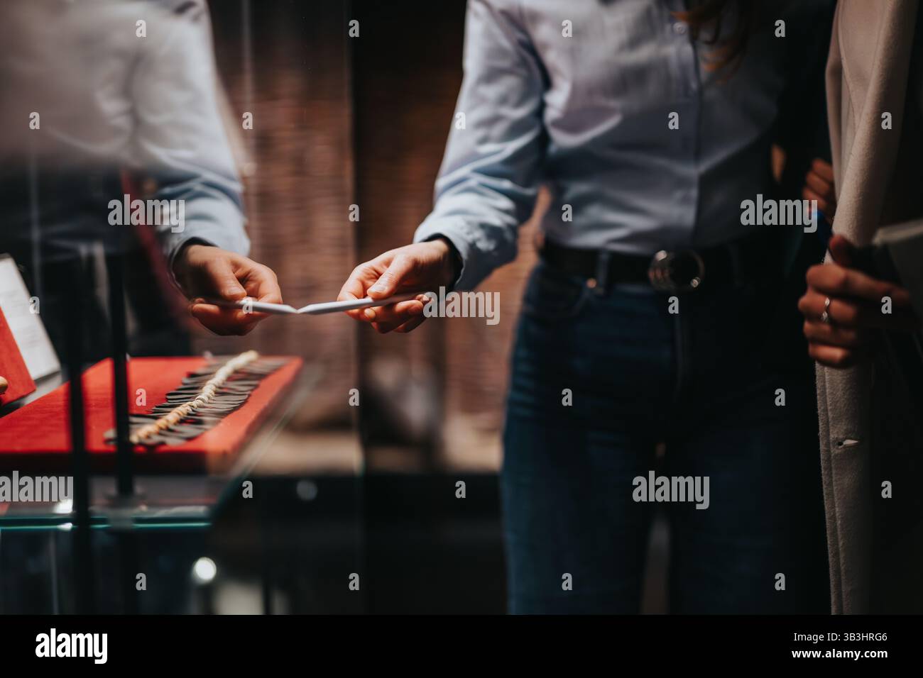 Two people examining exhibits at a museum with one handing over an ...