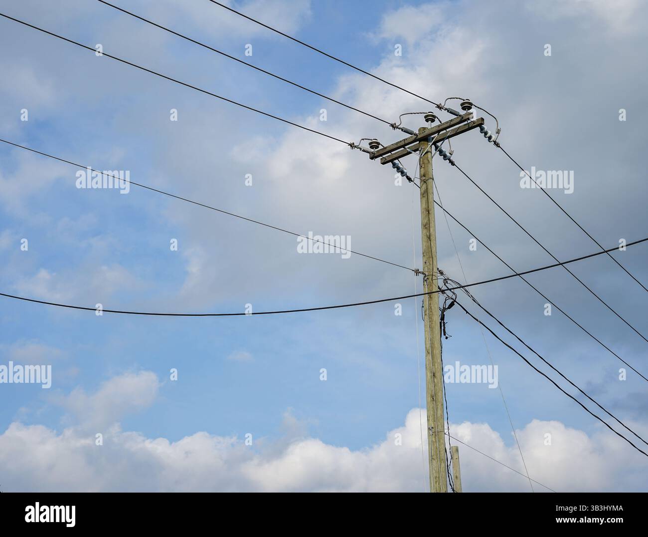 High voltage power lines, wires and racks, against a background of blue sky and white fluffy ...