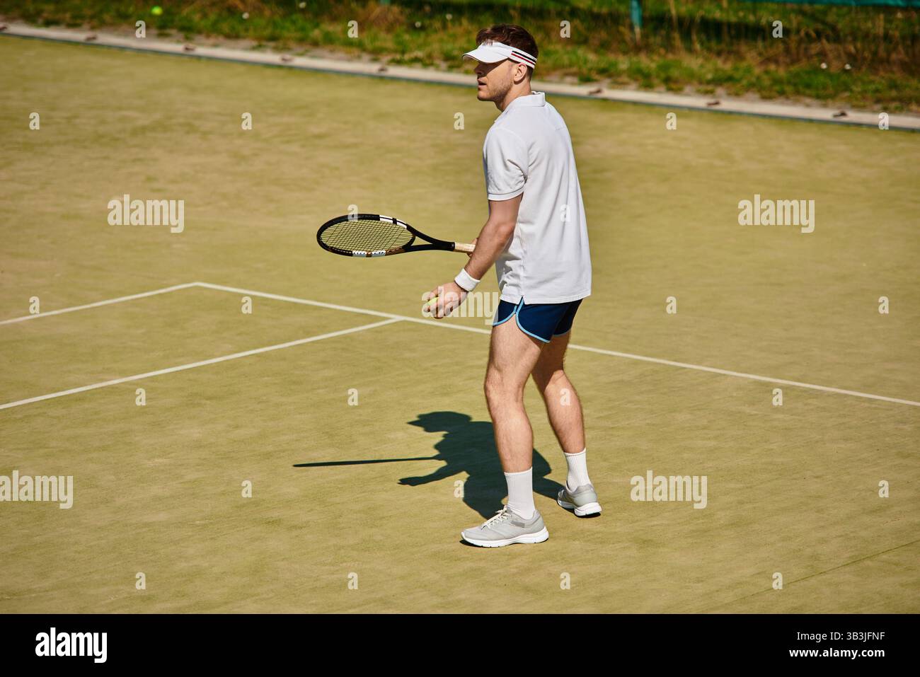 Focused athlete in white sportswear takes a stance on the tennis court ...